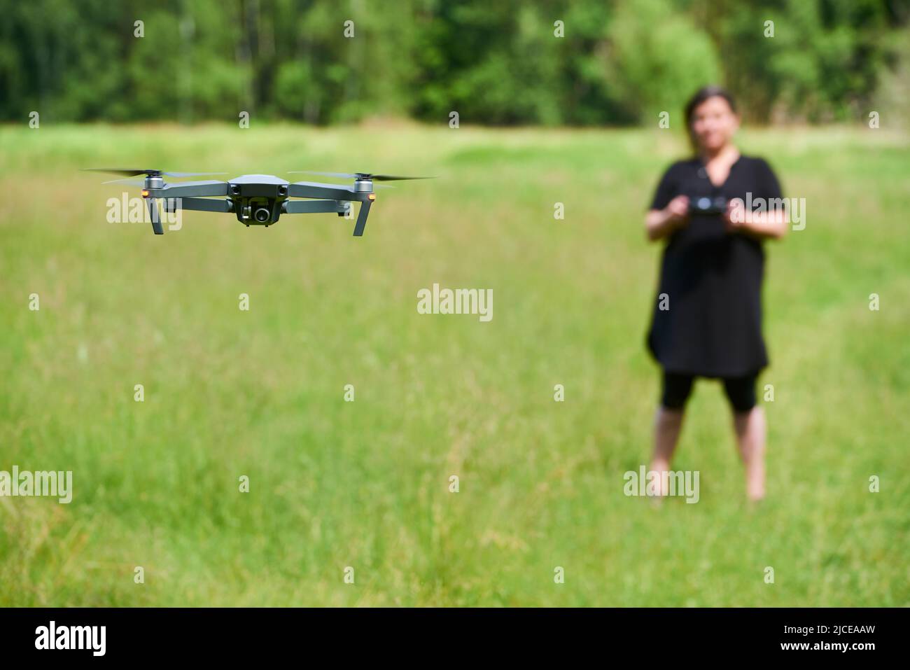 Young smiling woman pilot operating the drone by remote control. Flying ...