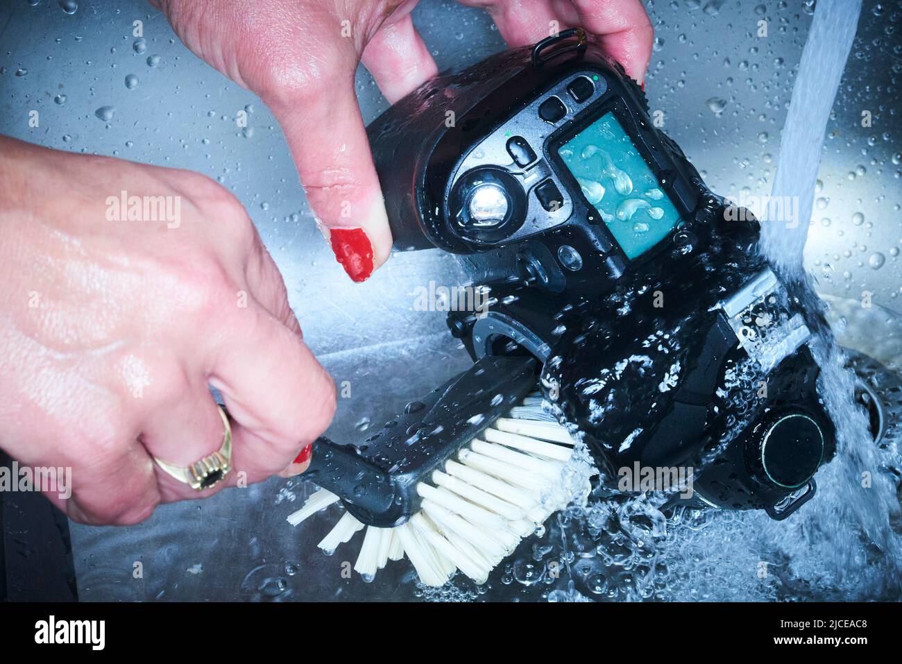 Female hands washing dslr camera as dirty dishes running water in the ...