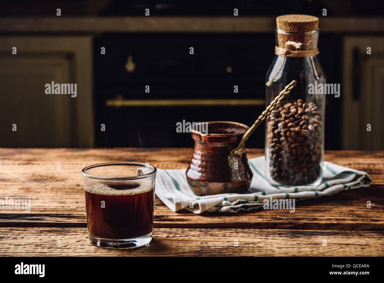Freshly brewed turkish coffee in drinking glass. Cezve and jar of ...