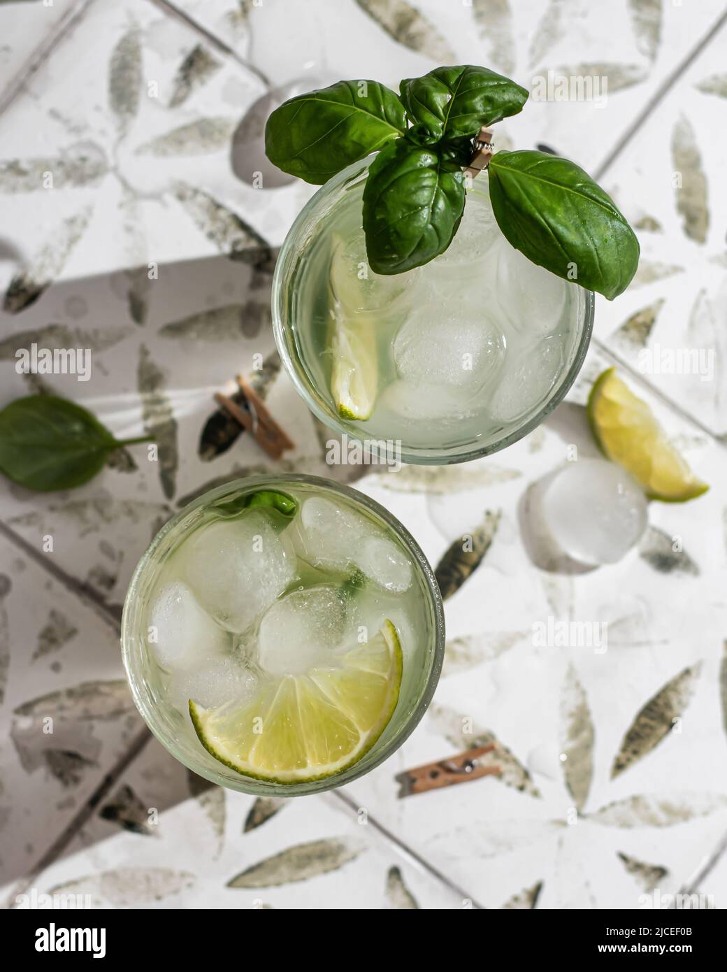 Two margarita cocktails with lime and basil on printed tile. Vertical ...