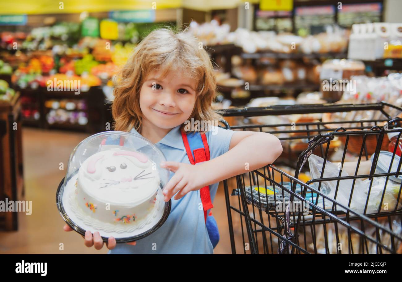 Child with shopping basket purchasing cake in a grocery store ...