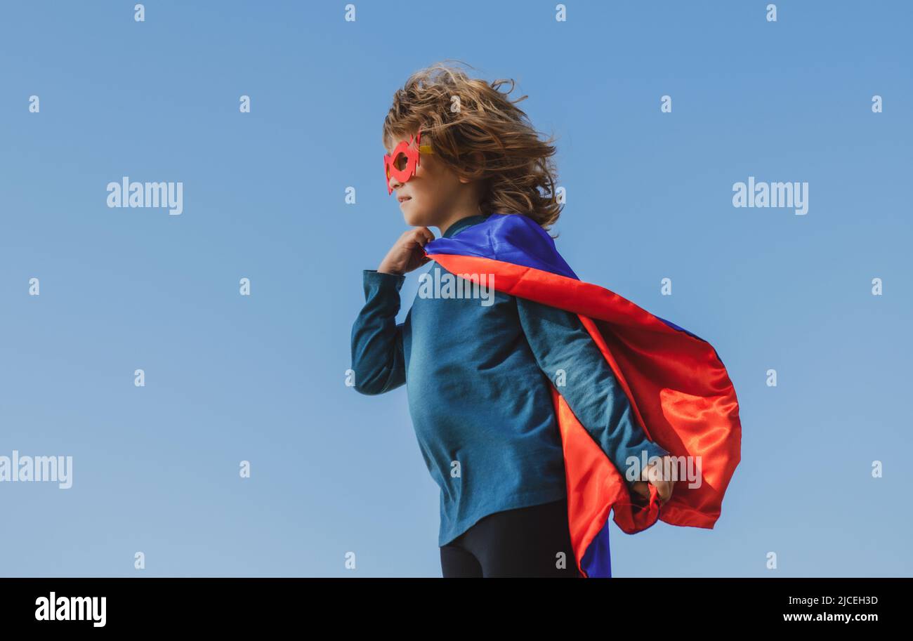 Child wearing a superhero costume. Super hero child against blue summer ...
