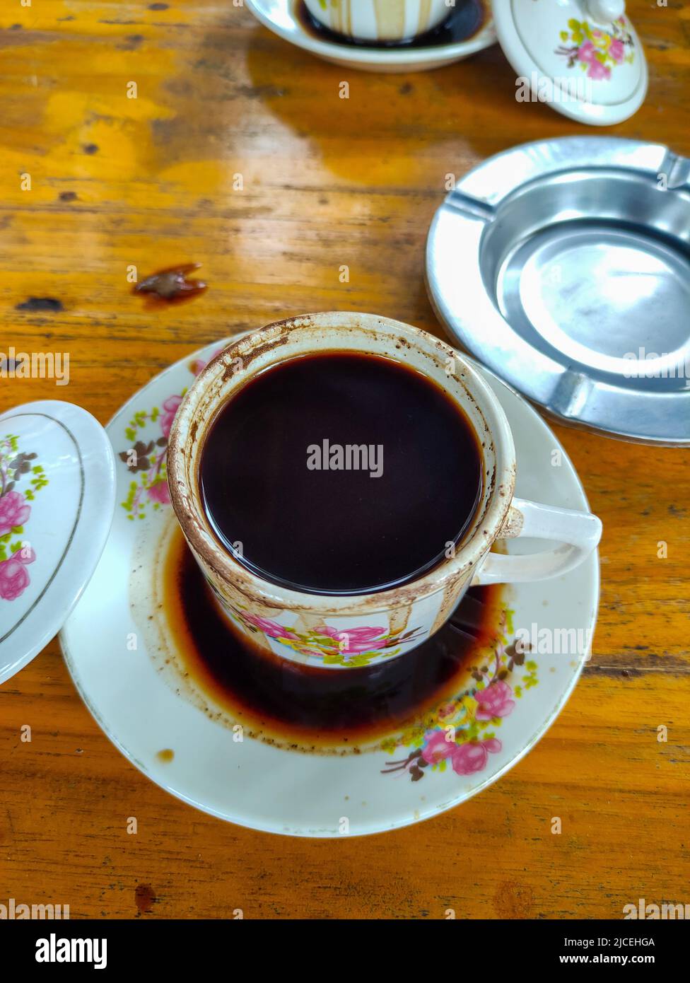 White cup of hot balck coffee on wood background with ashtray and ...