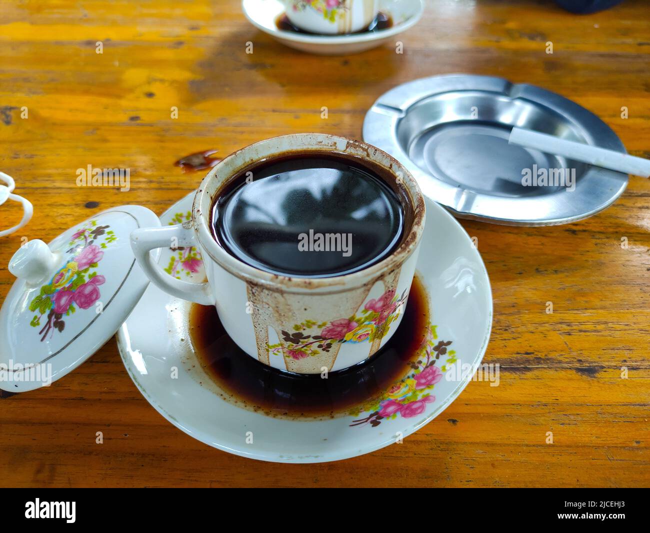White cup of hot balck coffee on wood background with ashtray and ...