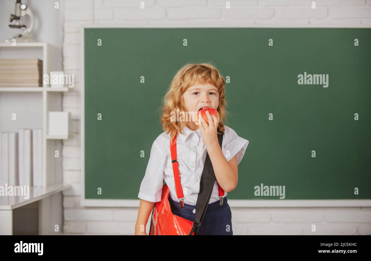 Little school boy student eating apple learning in class, study english ...