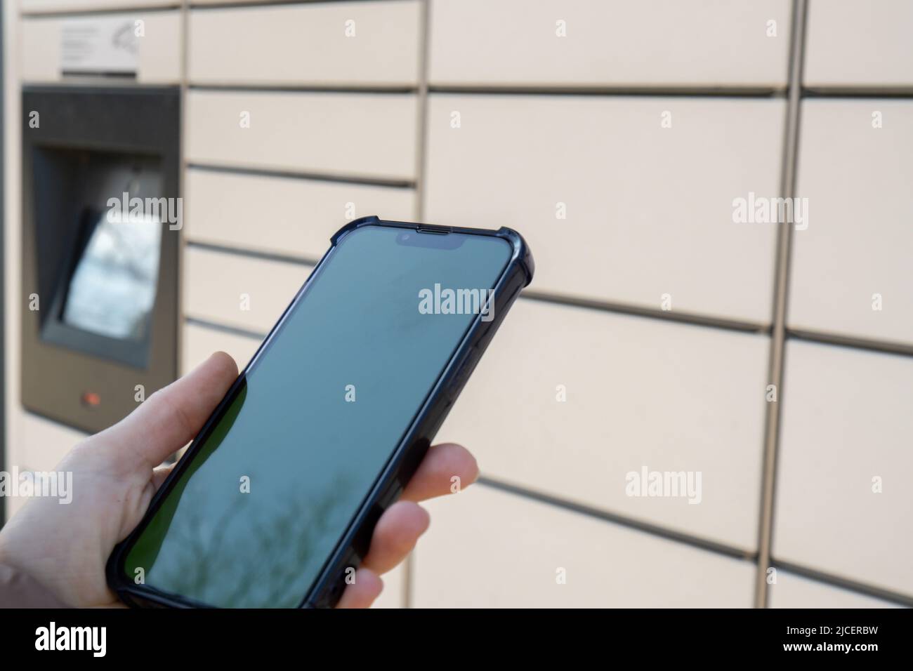 Female hand holding mobile phone next to Parcel locker Collecting ...