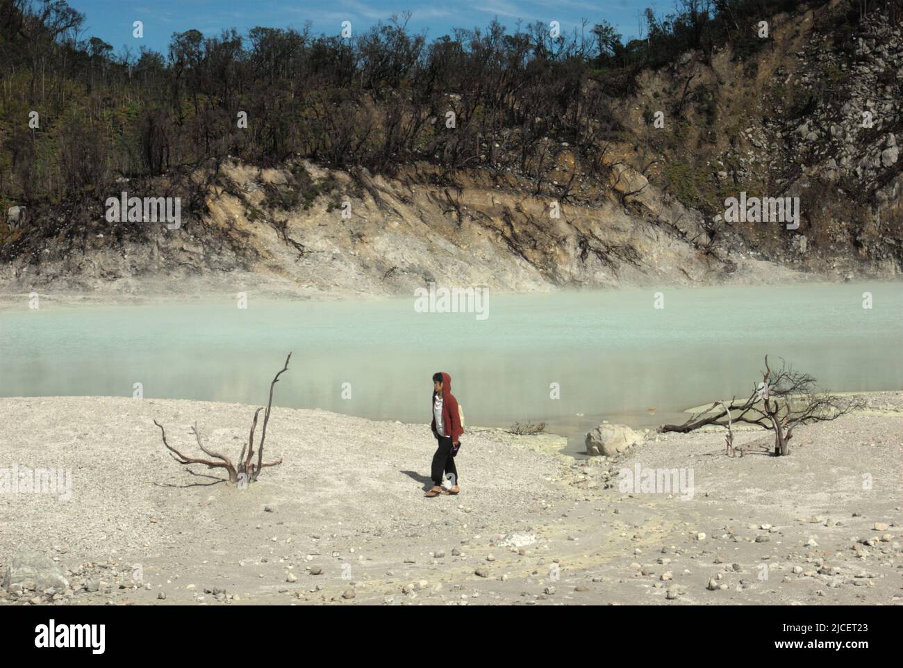 A woman walking on sandy landscape on the crater of Mount Patuha, which ...