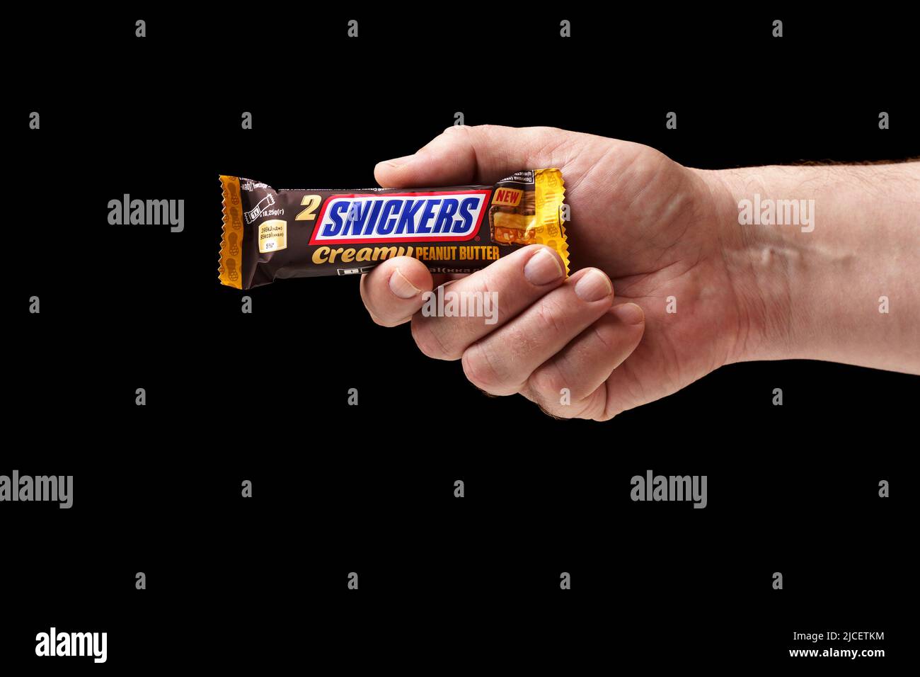 Hand holding a chocolate bar close-up. A man offers a Snickers ...