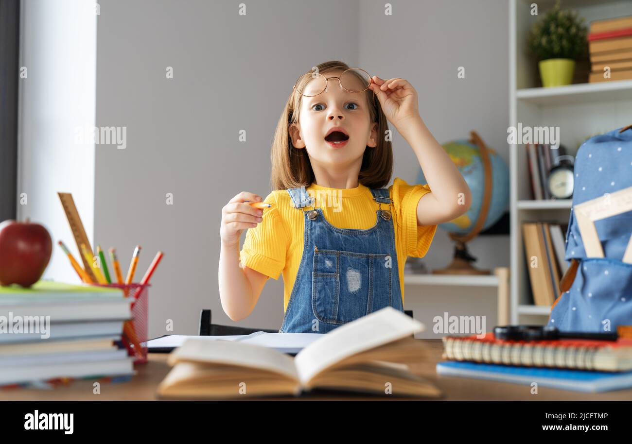 Back to school! Happy cute industrious child is sitting at a desk ...