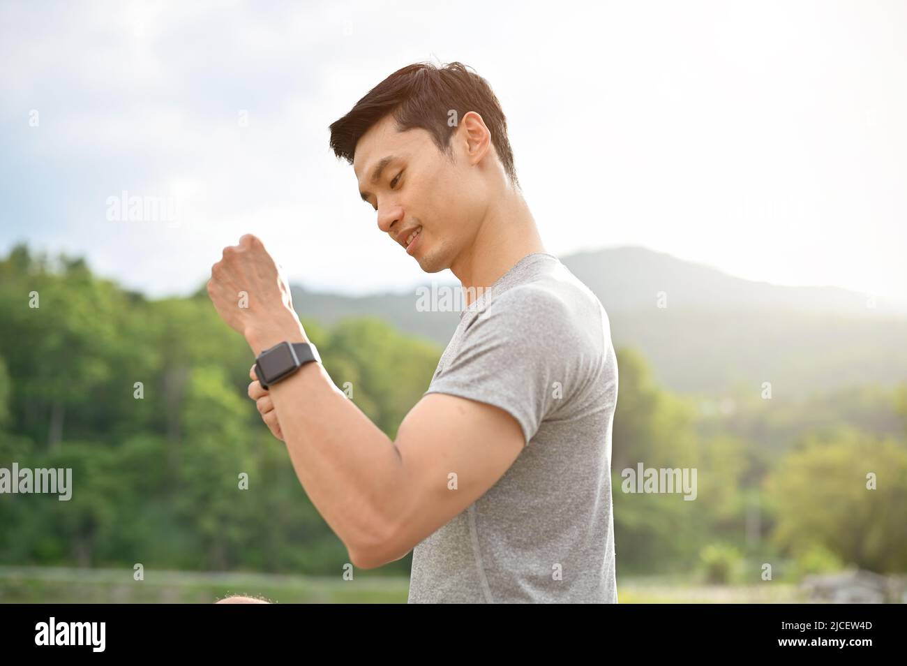 Sporty and handsome Asian man in a sportswear with his sport smartwatch ...
