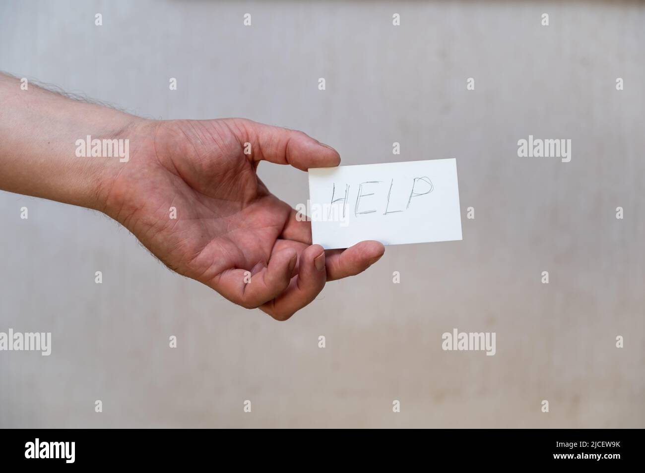 Help. The word is written in uneven letters. A man's hand holds a white ...