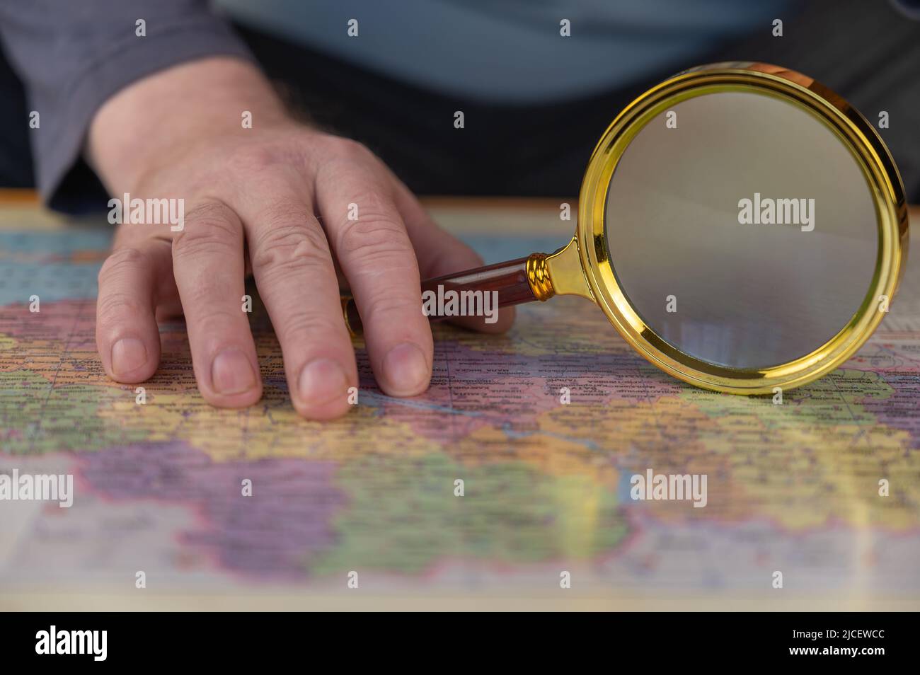 A man holds a magnifying glass in his hand over a map. A middle-aged ...