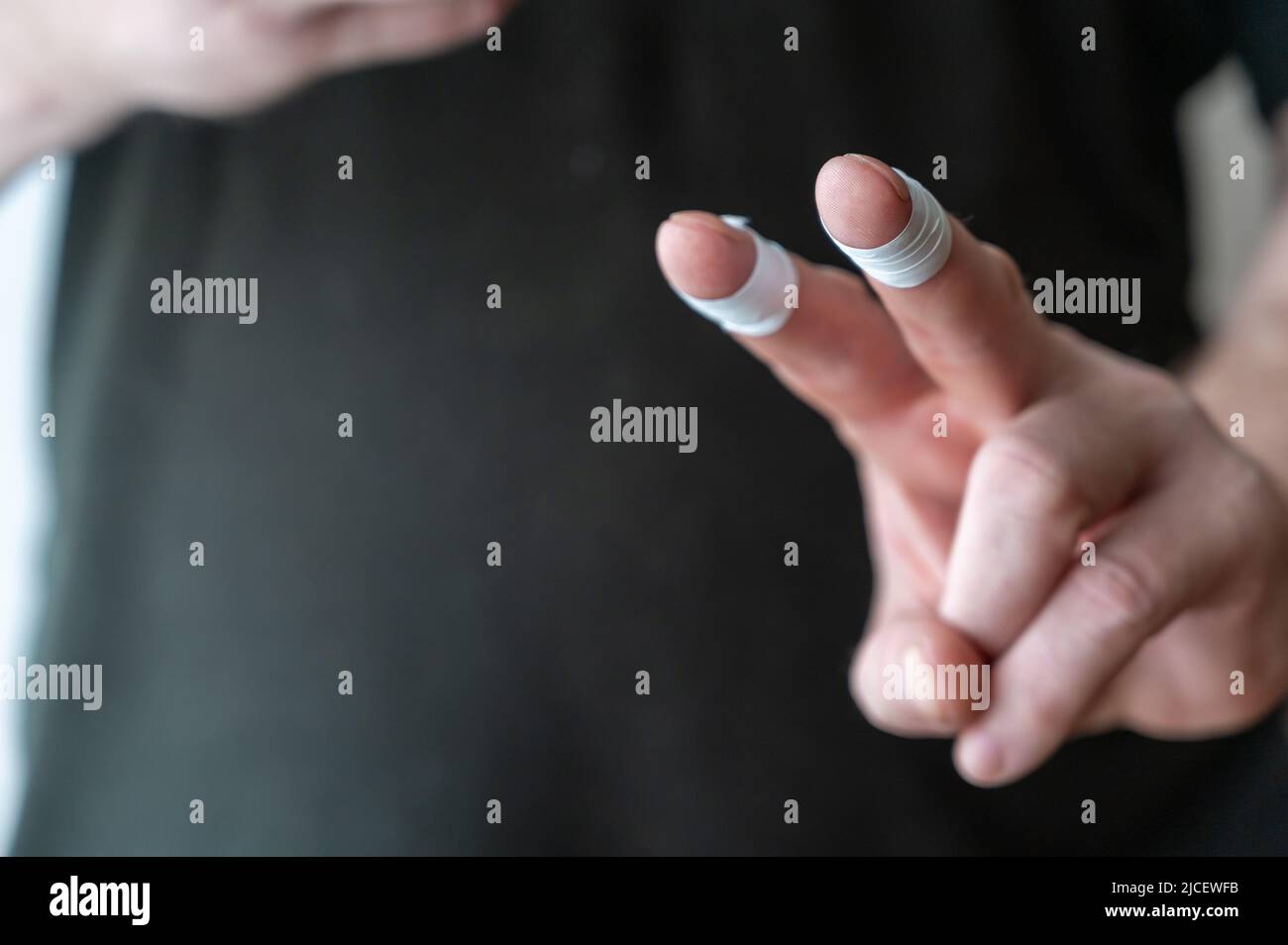 Close-up of a man's hand showing a gesture of victory. White armbands ...