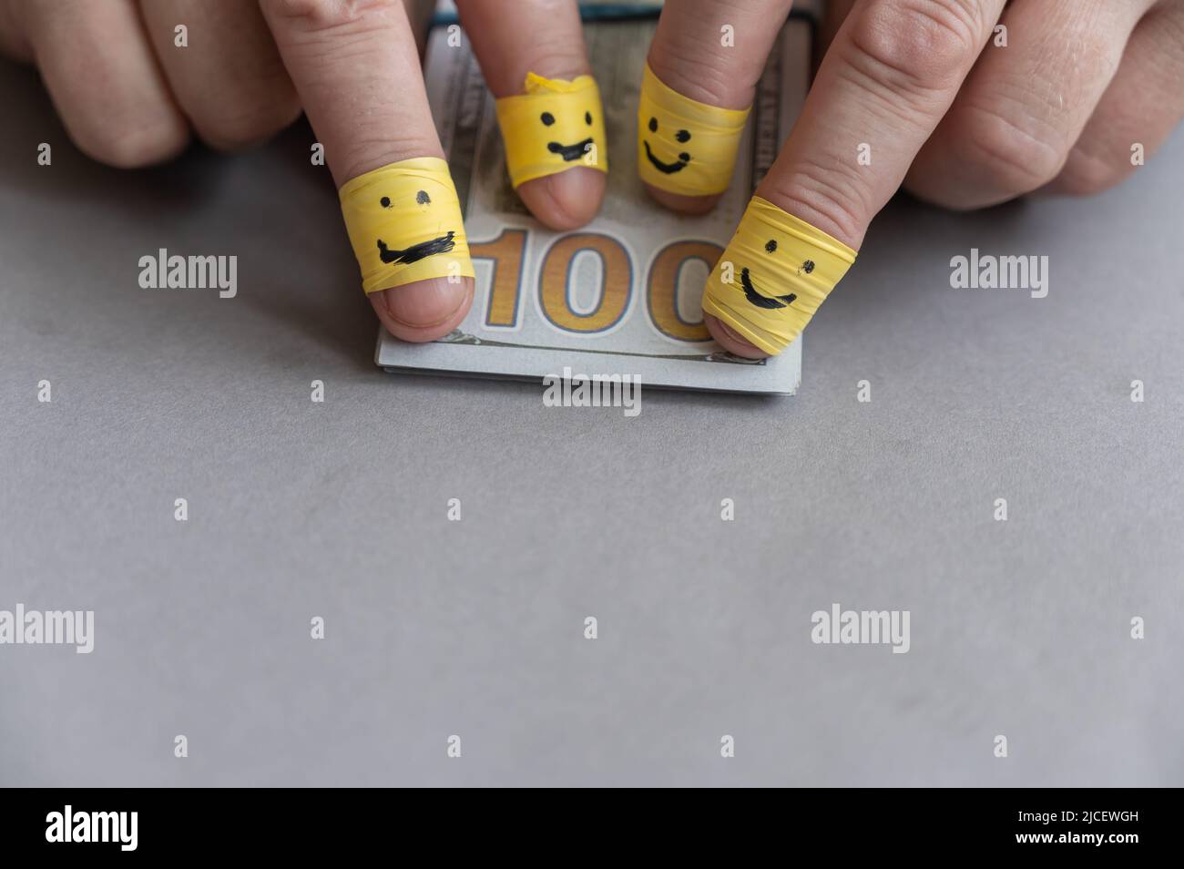 Man's fingers lie on money against gray background. Wad of American ...
