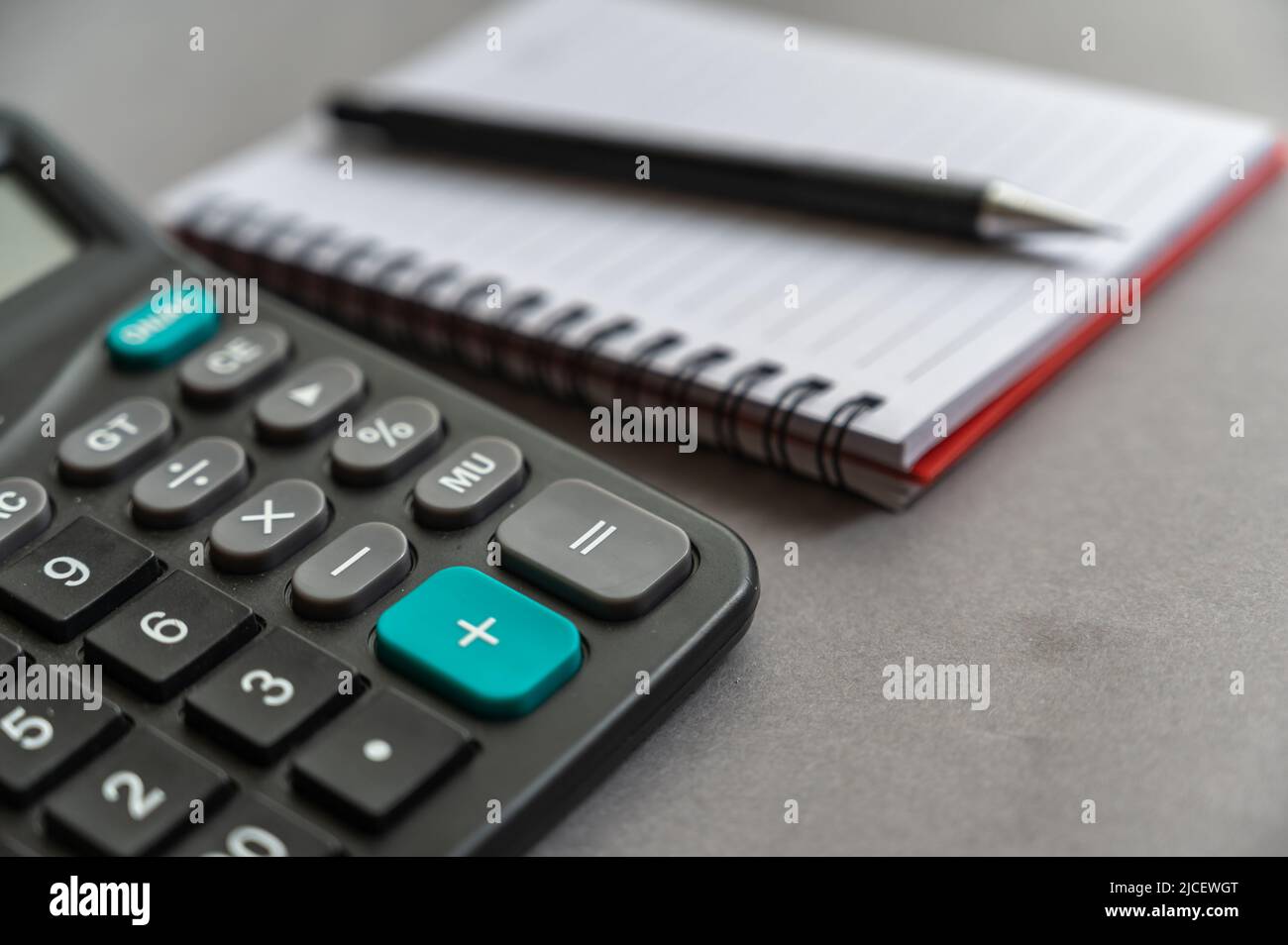 Calculator, pen, notepad lie on a gray surface. Open spring-loaded ...