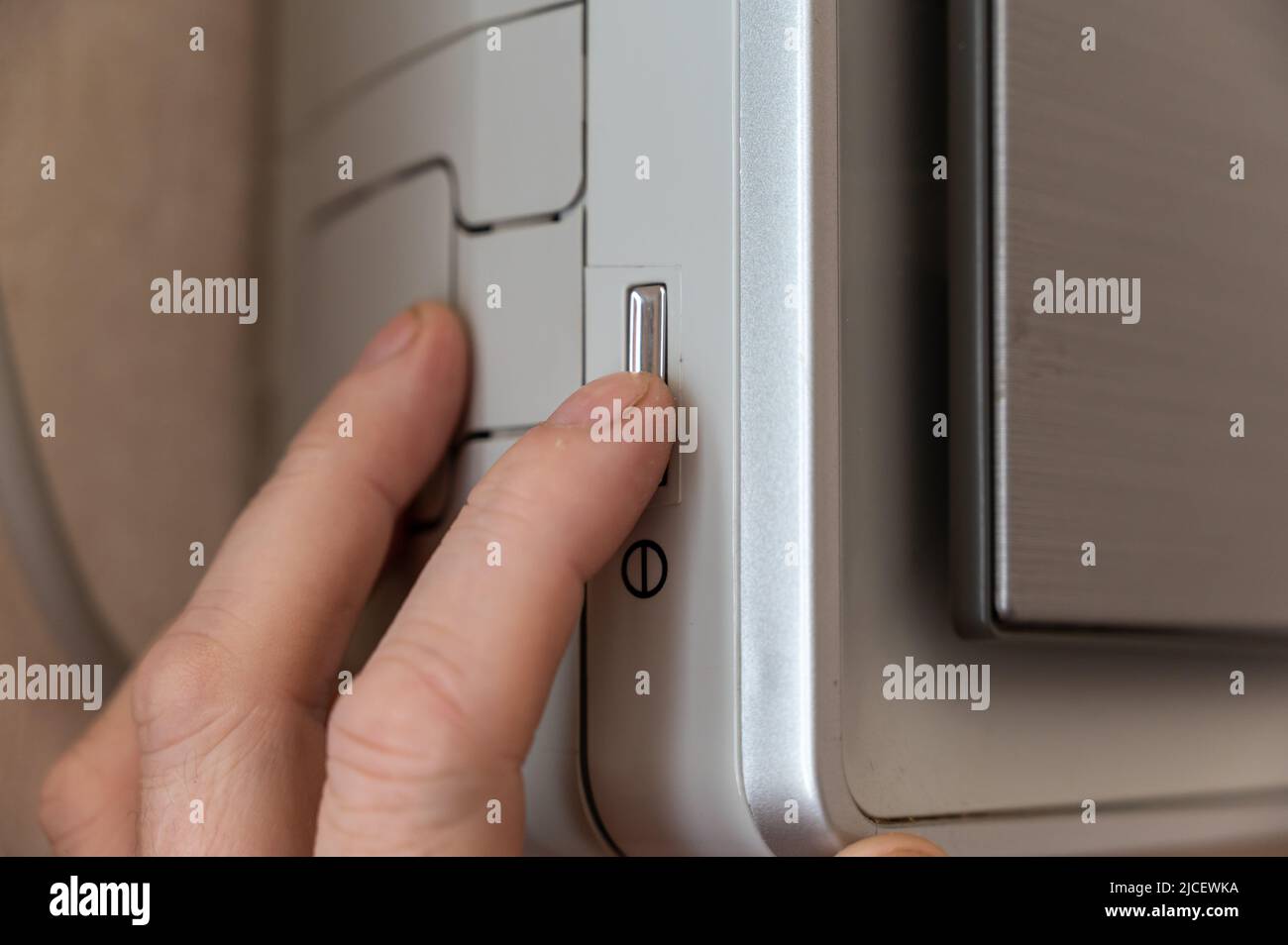 Man turns on indoor air conditioner. His index finger presses the ...