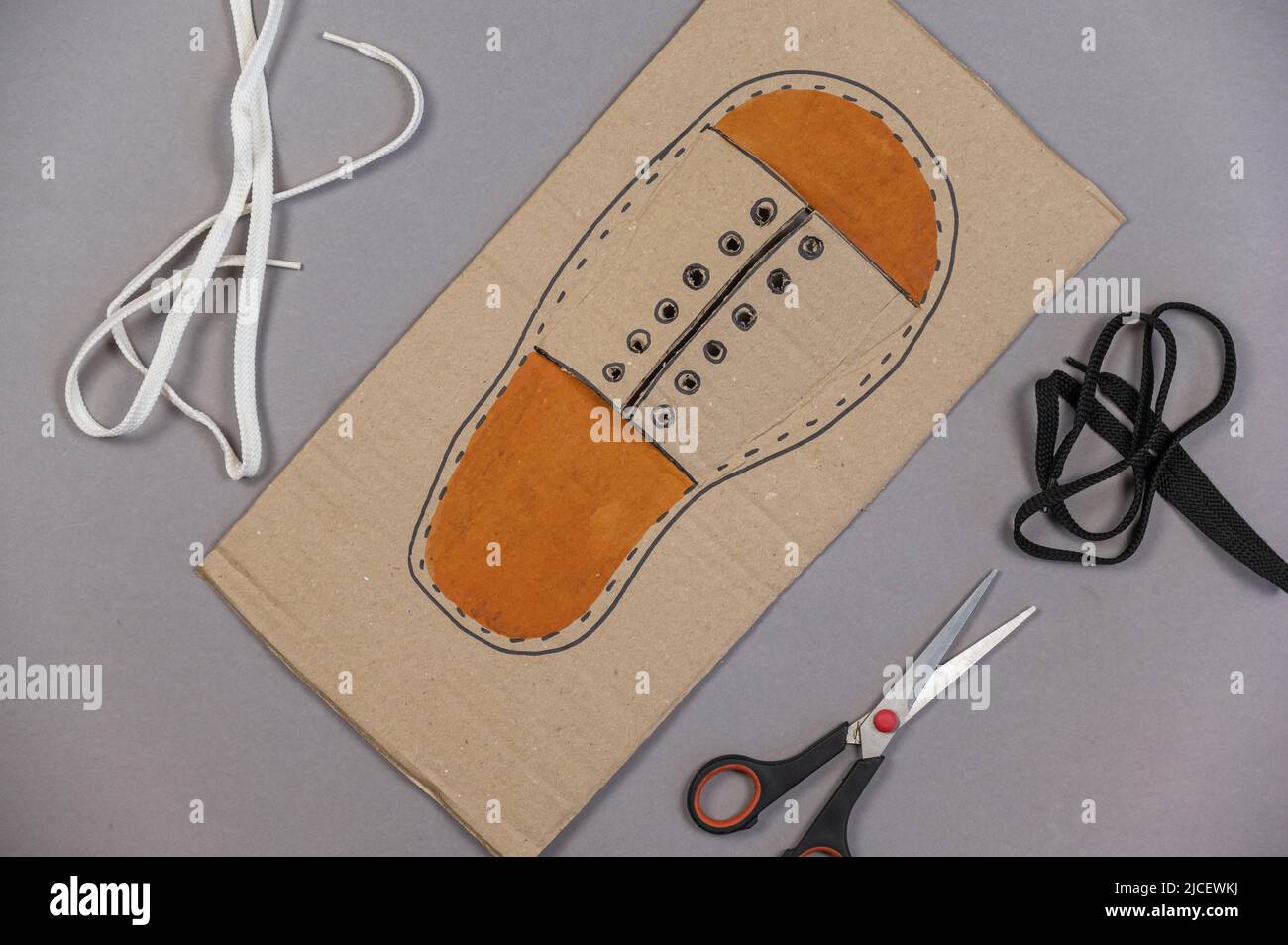 A card for tying laces and scissors against a gray background. Black ...
