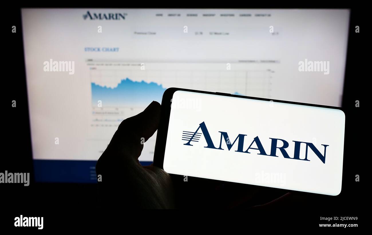 Person holding mobile phone with logo of biopharmaceutical company Amarin Corporation plc on ...