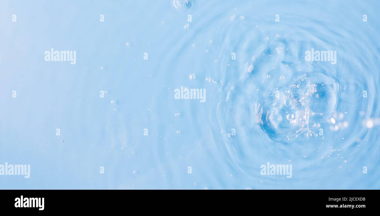 Pouring and splashing clear water on light blue background upper close ...