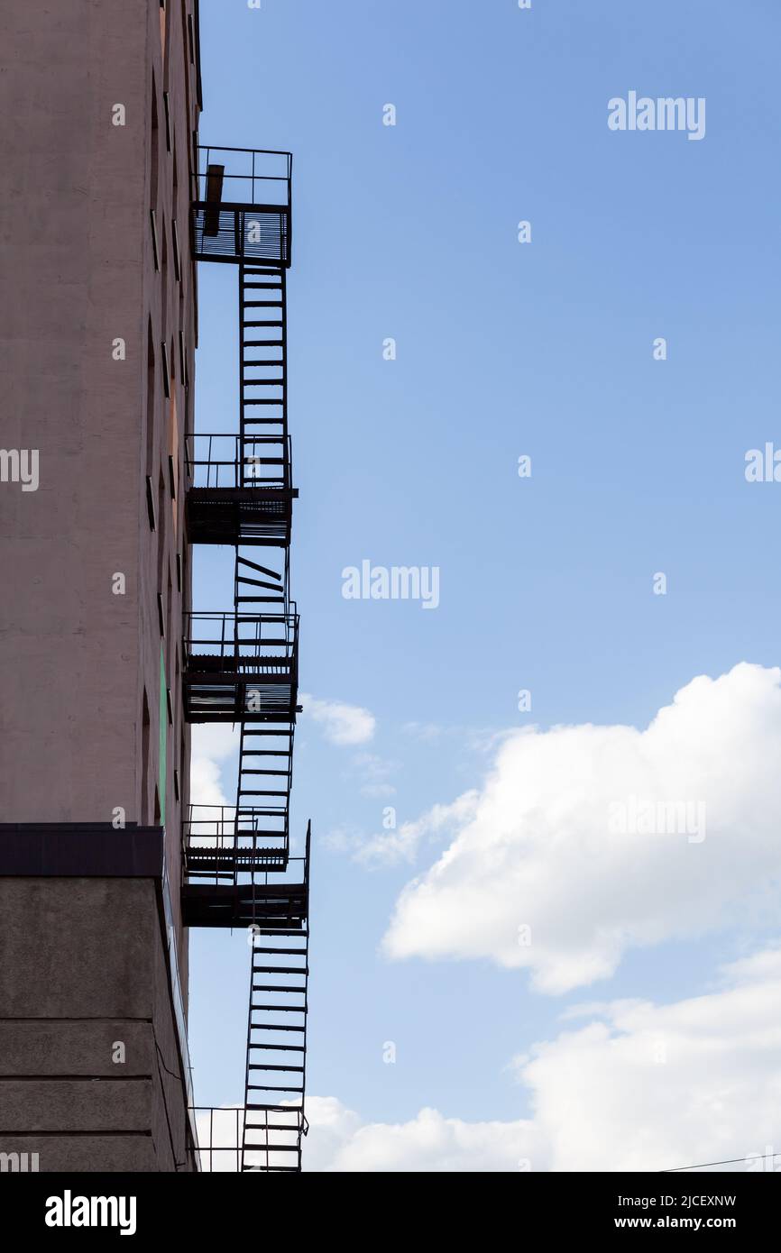 Silhouette of a fire escape on a high-rise building against a blue sky ...