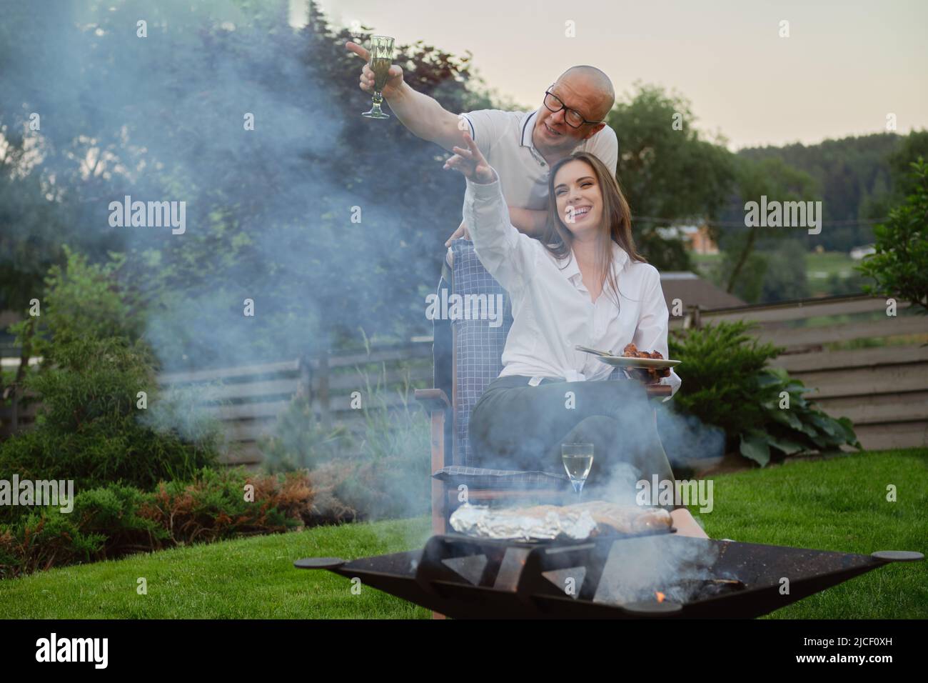 Happy couple having barbecue picnic on backyard. People pointing or ...