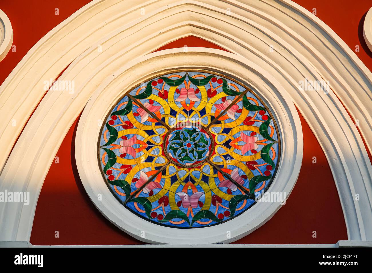 Close-up of a colorful round window over church entrance with white ...