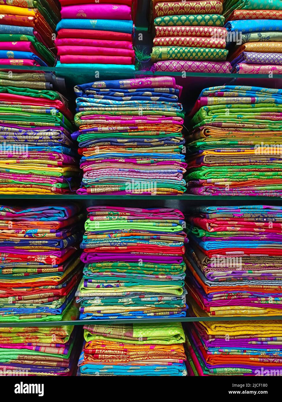 Closeup view of stacked colours saris or sarees in display of Indian ...