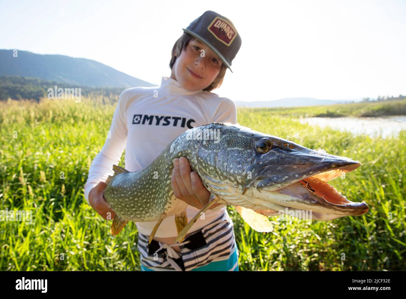 Boy with his catch, a giant pike fish that he caught in summer time on ...