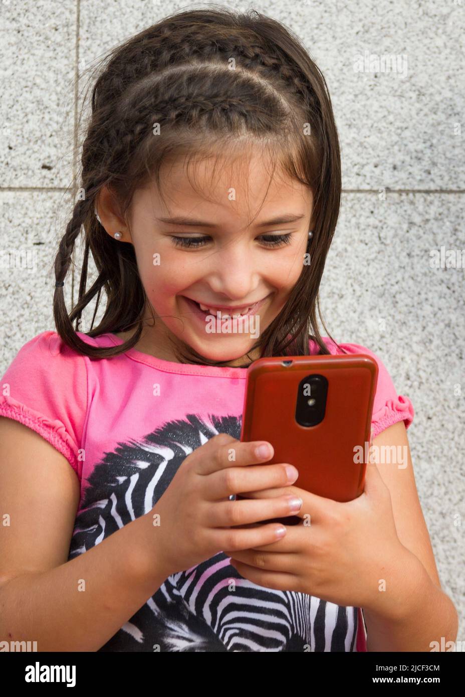 Happy little girl looking at cell phone. Smiling young kid holding ...