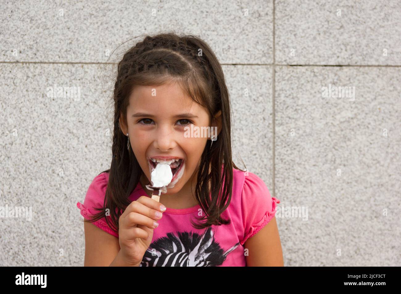 Little girl laughing while eating chocolate ice cream. Smiling young ...