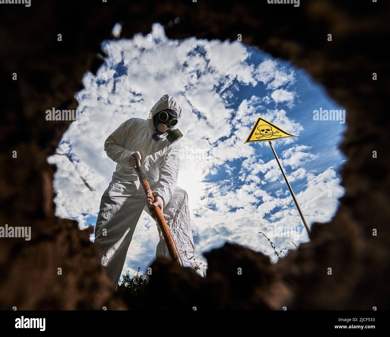 View from inside pit of male scientist in protective wear and gas mask ...