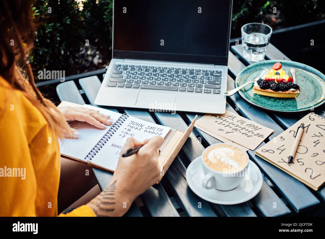 Woman numerologist working with numbers in notepad and laptop ...