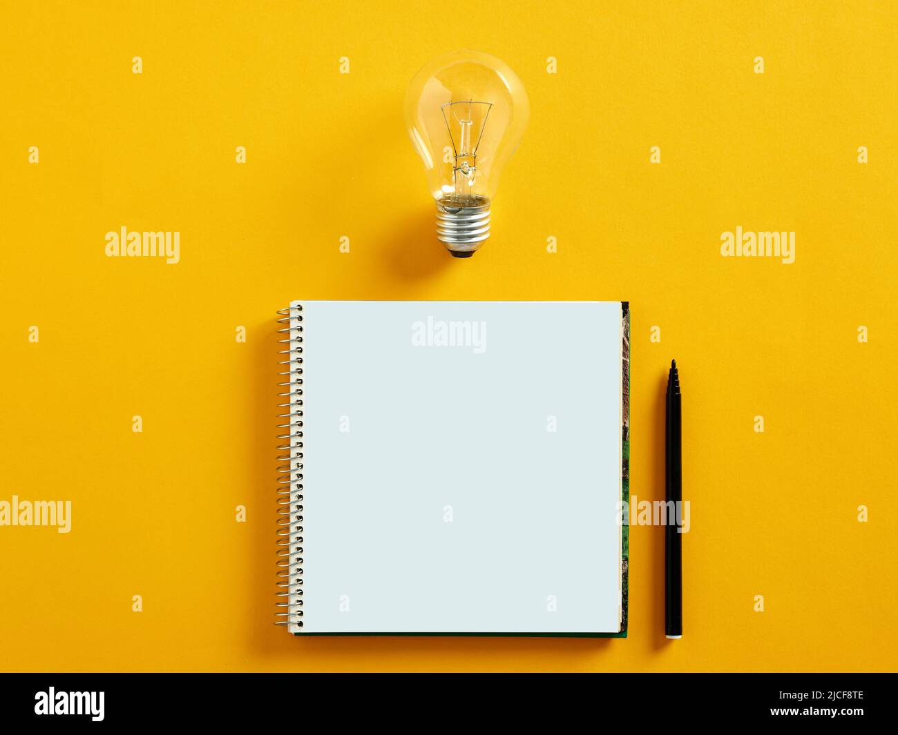 Blank notebook, pen and a light bulb on yellow background ...
