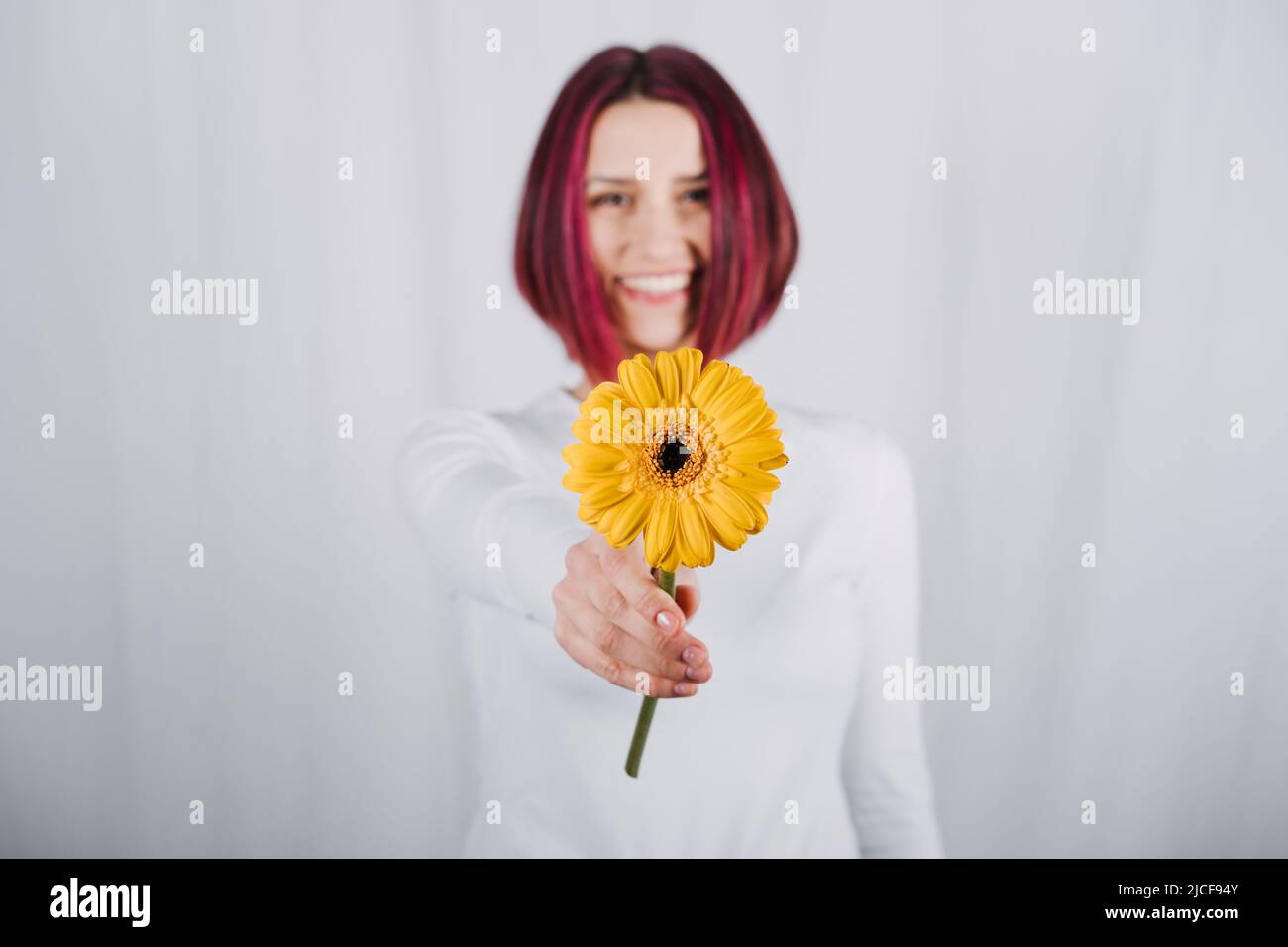 Studio portrait millennial woman with bright red Color hair and yellow ...