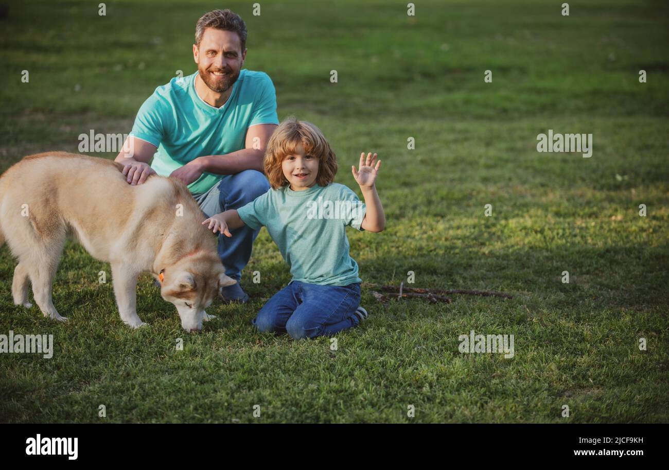 Son and father as family with dog playing together in summer park on ...