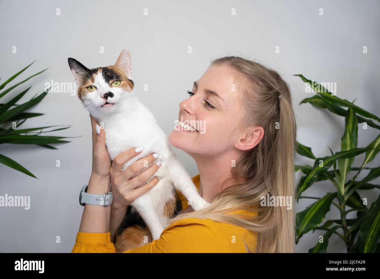 young blond woman carrying her cat trying to embrace the cat that ...