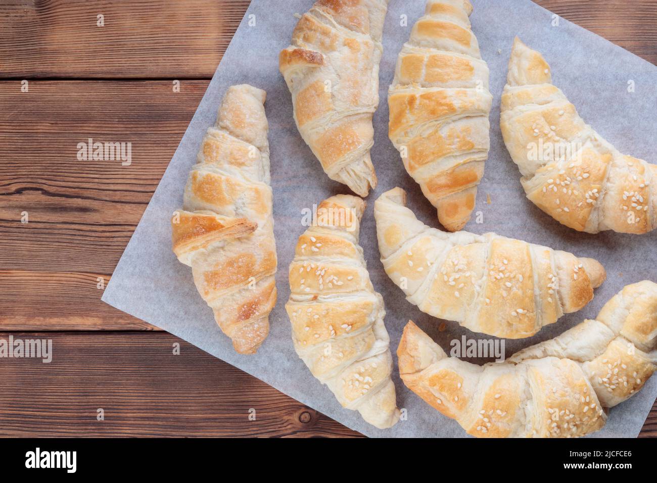 Homemade croissants on a baking paper on wooden background Stock Photo ...