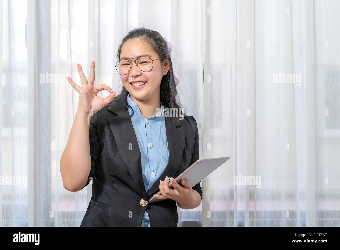 OK gesture poses from an Asian beauty woman with a Tablet computer, mobile and a control ...