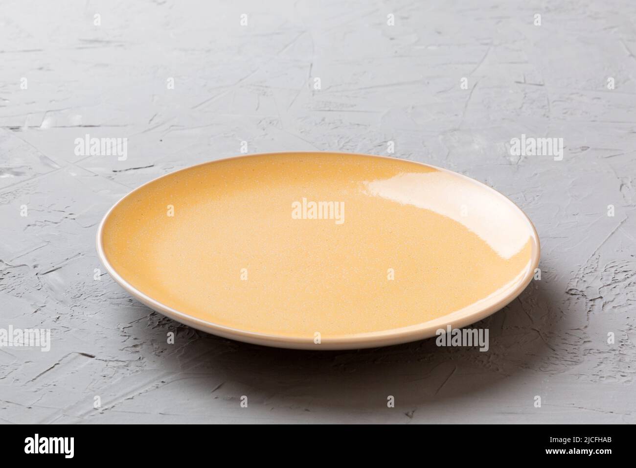 Perspective view of empty orange plate on cement background. Empty ...