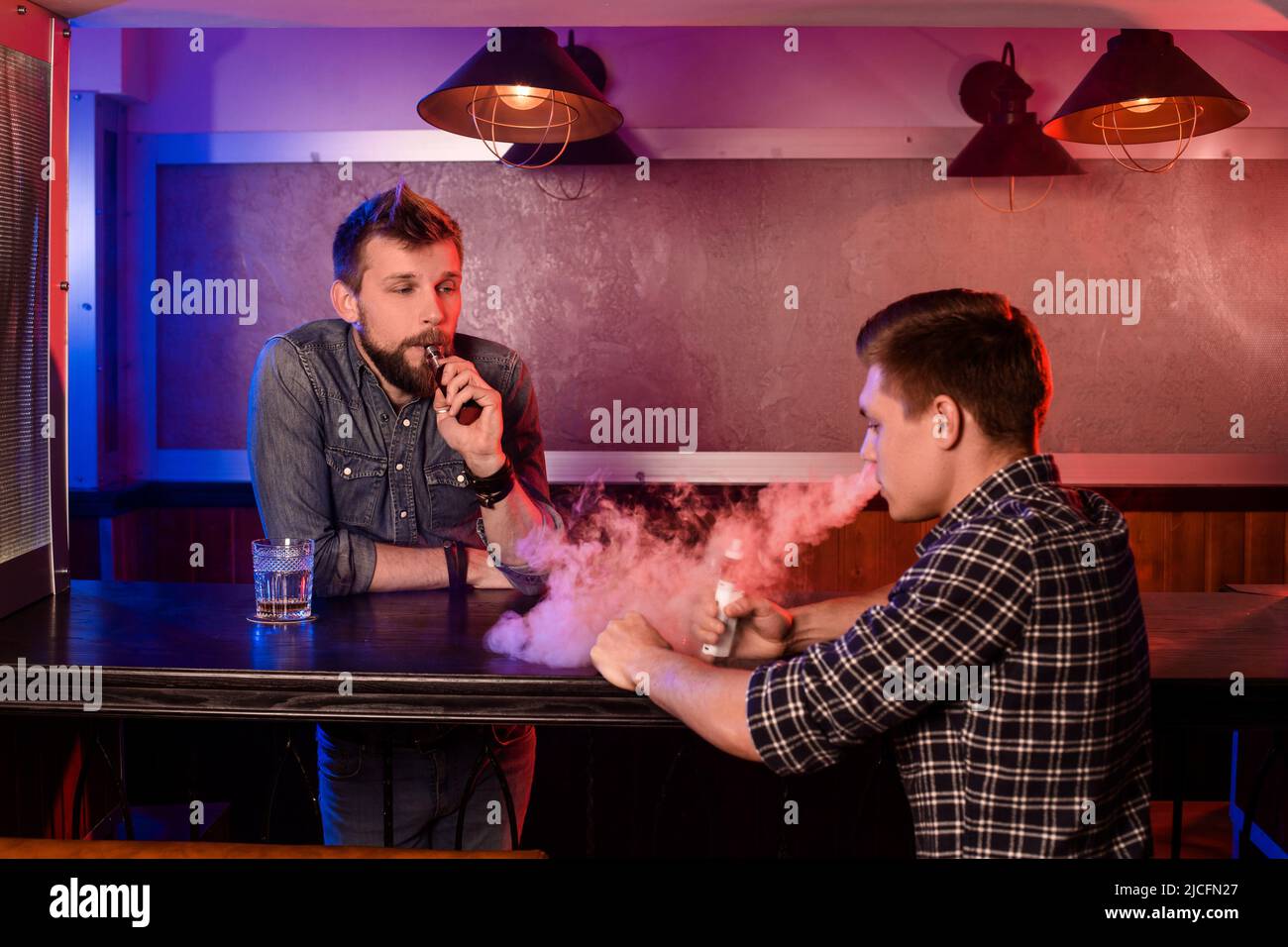 Vaping man holding a mod. A cloud of vapor at the vapebar Stock Photo ...