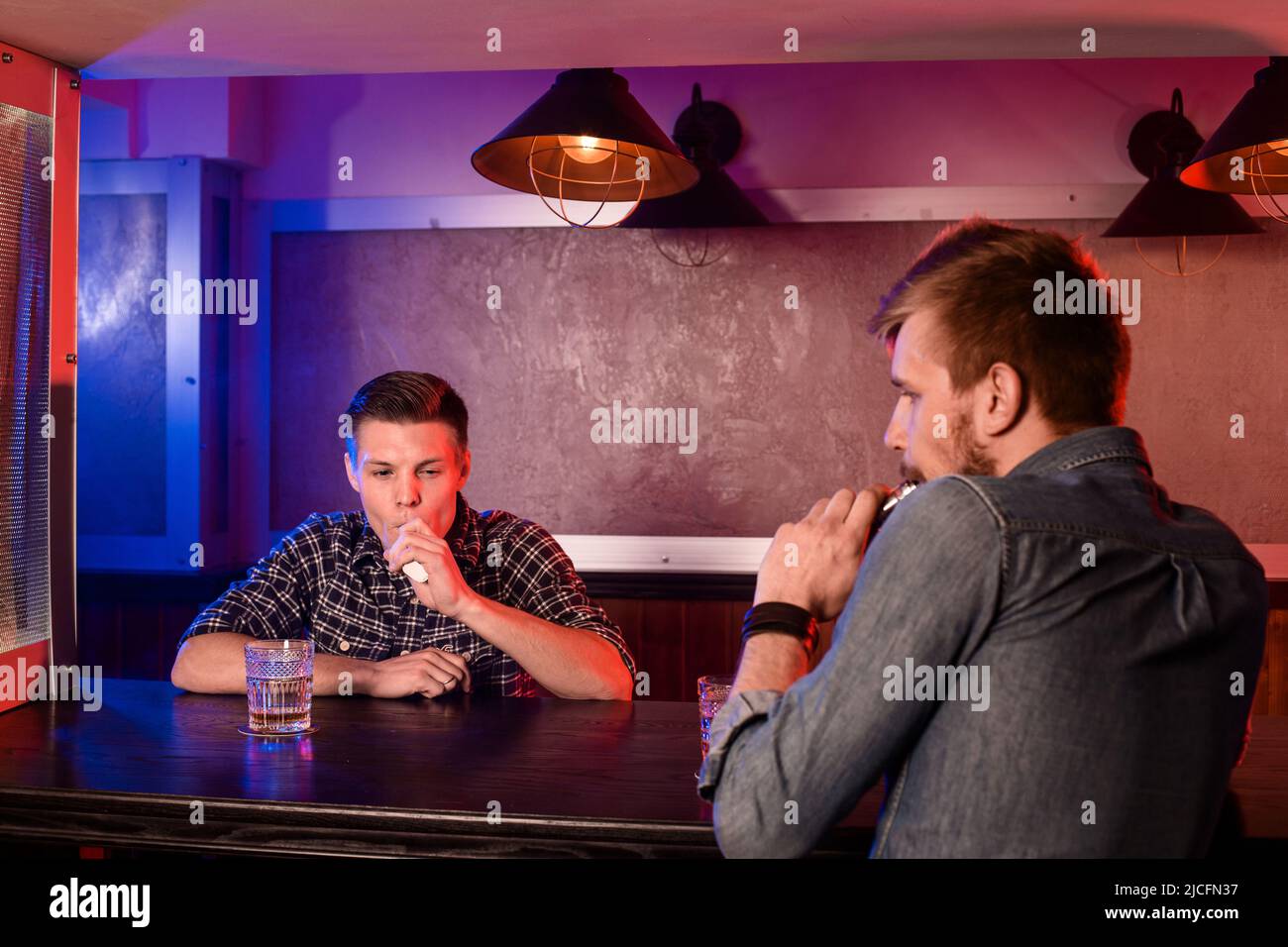 Two young men smoke electronic cigarettes in a vapebar Stock Photo - Alamy