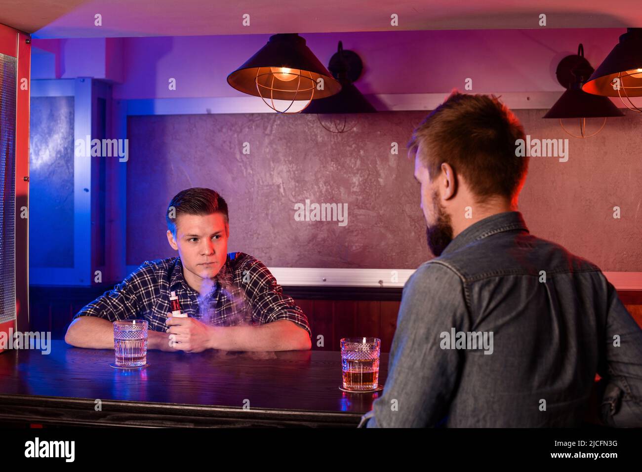 Two young men smoke electronic cigarettes in a vapebar Stock Photo - Alamy
