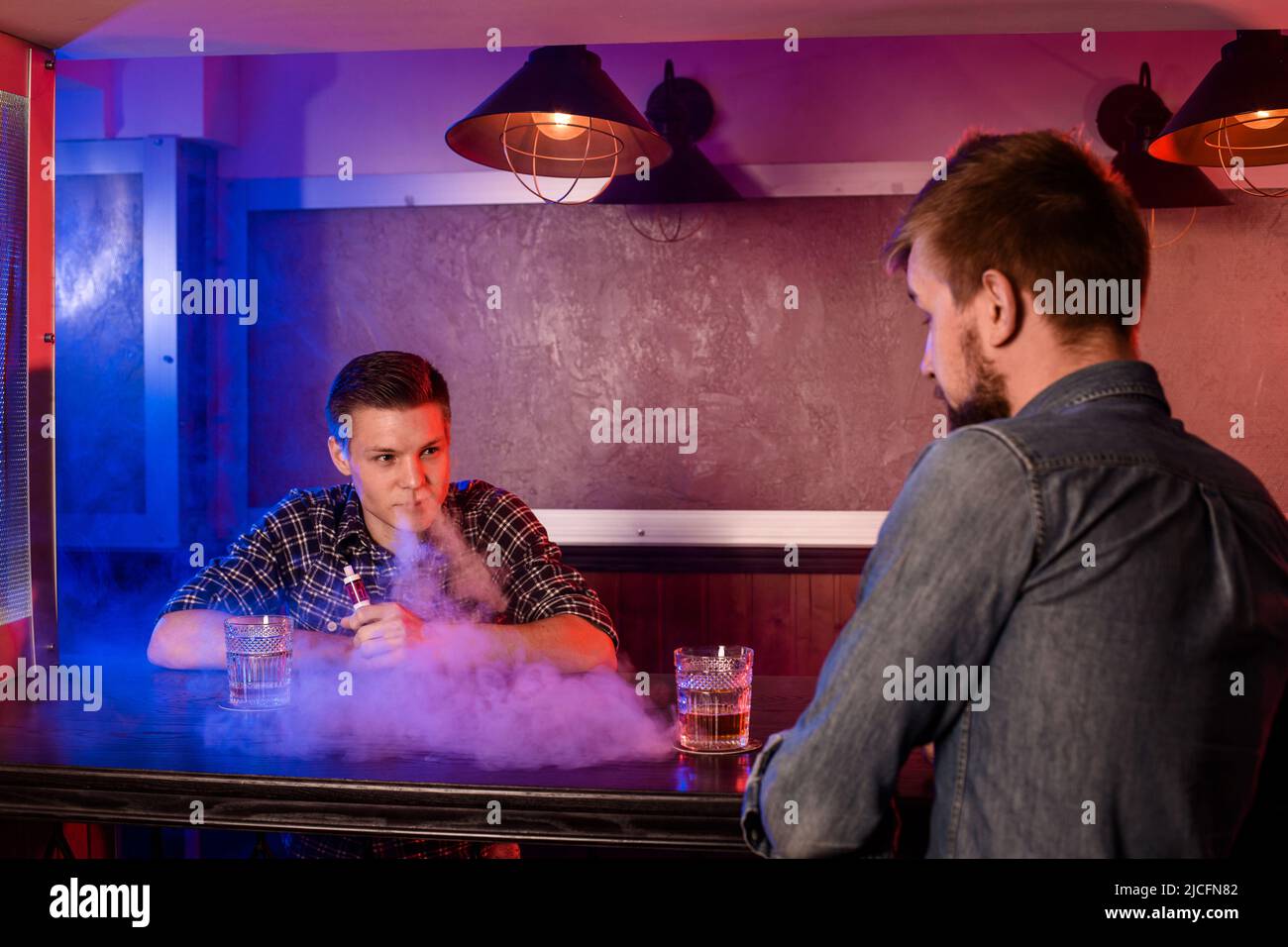 Two young men smoke electronic cigarettes in a vapebar Stock Photo - Alamy