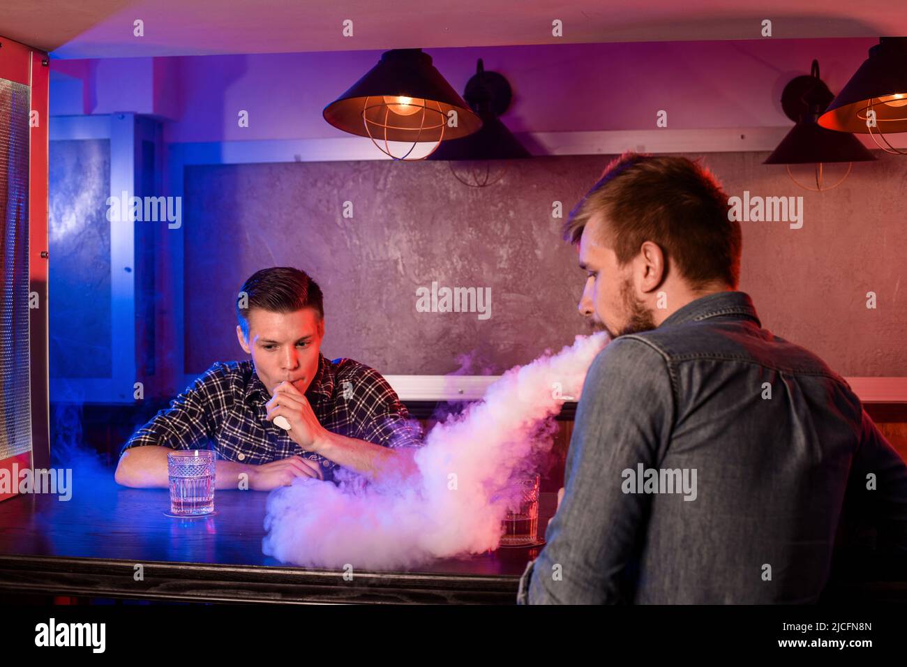 Two young men smoke electronic cigarettes in a vapebar Stock Photo - Alamy