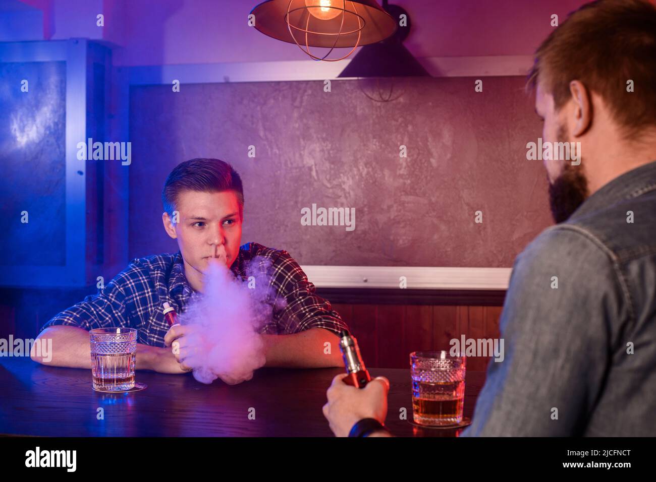 Two young men smoke electronic cigarettes in a vapebar Stock Photo - Alamy