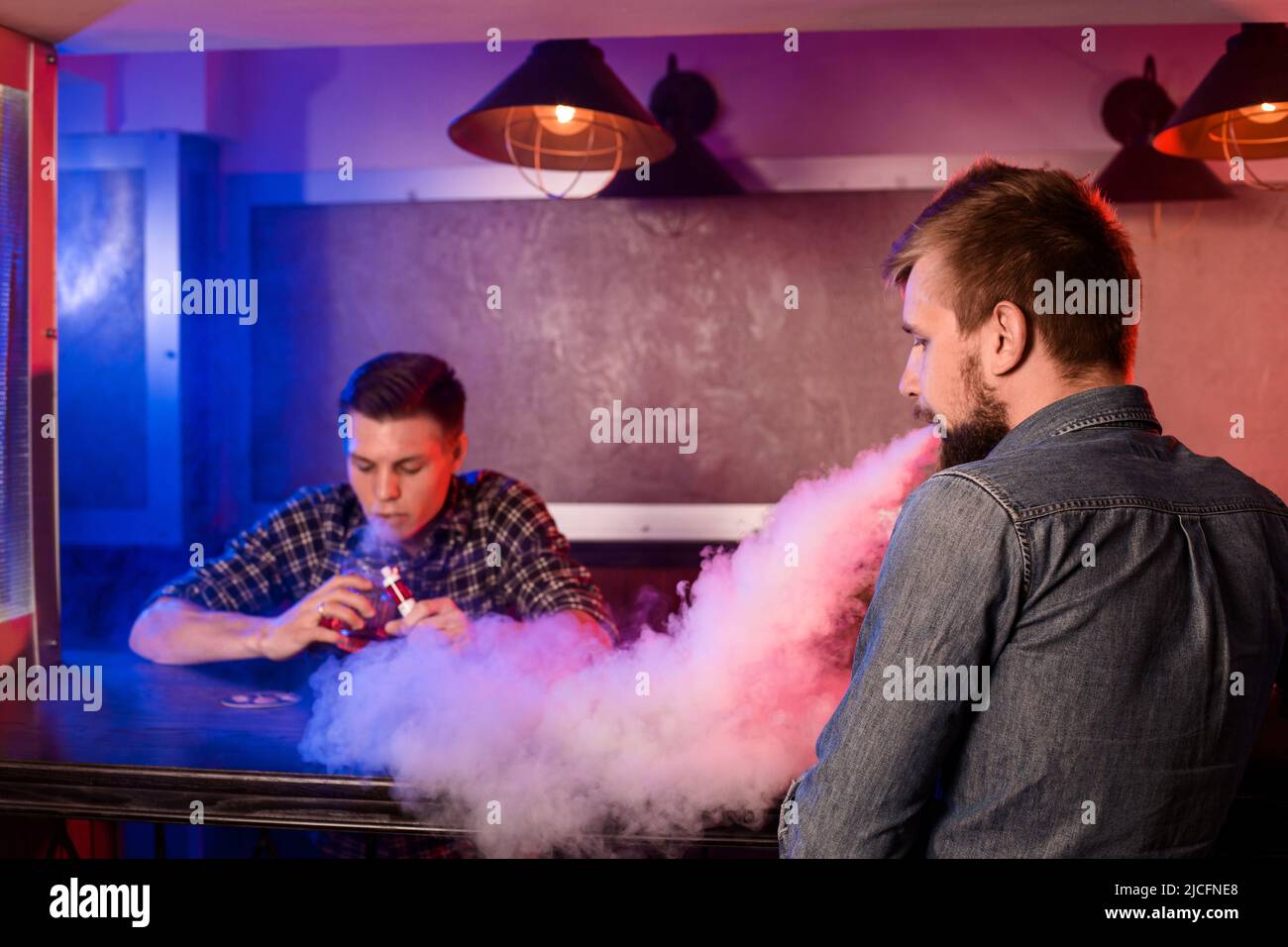 Two young men smoke electronic cigarettes in a vapebar Stock Photo - Alamy