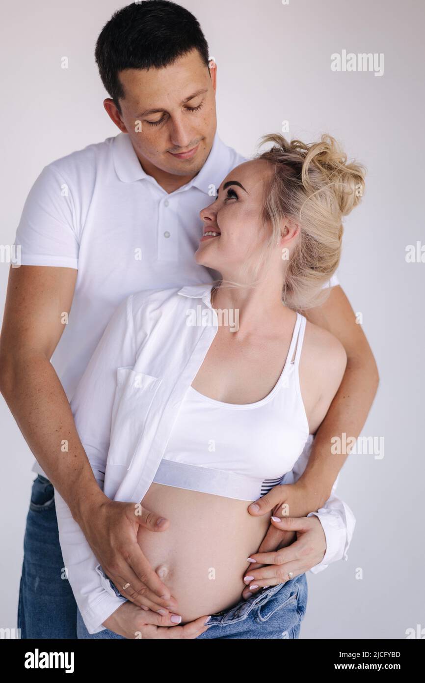 Happy future parents of man and pregnant woman puts hands on belly and waiting for beby movement ...