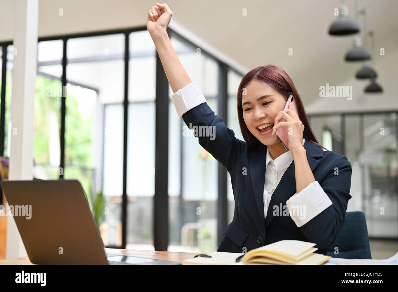 Excited asian businesswoman smiling, talking on the mobile phone and ...