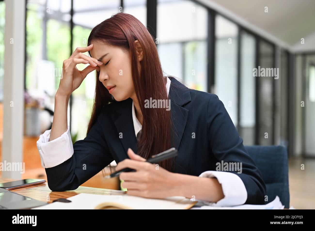 Tired asian businesswoman or female office worker is suffering from ...