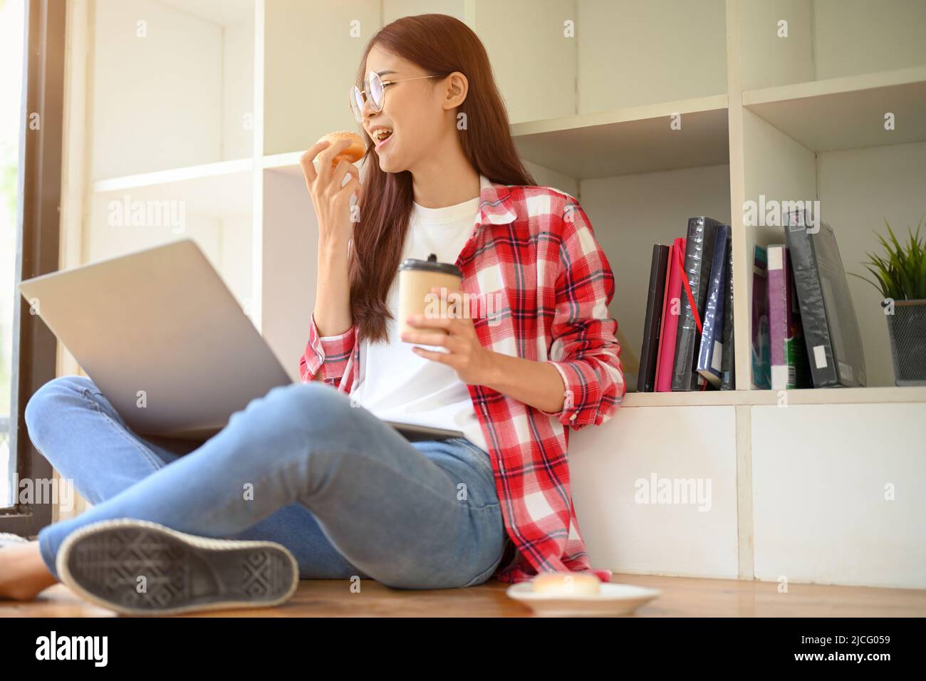 Pretty young asian female college student doing homework on portable ...